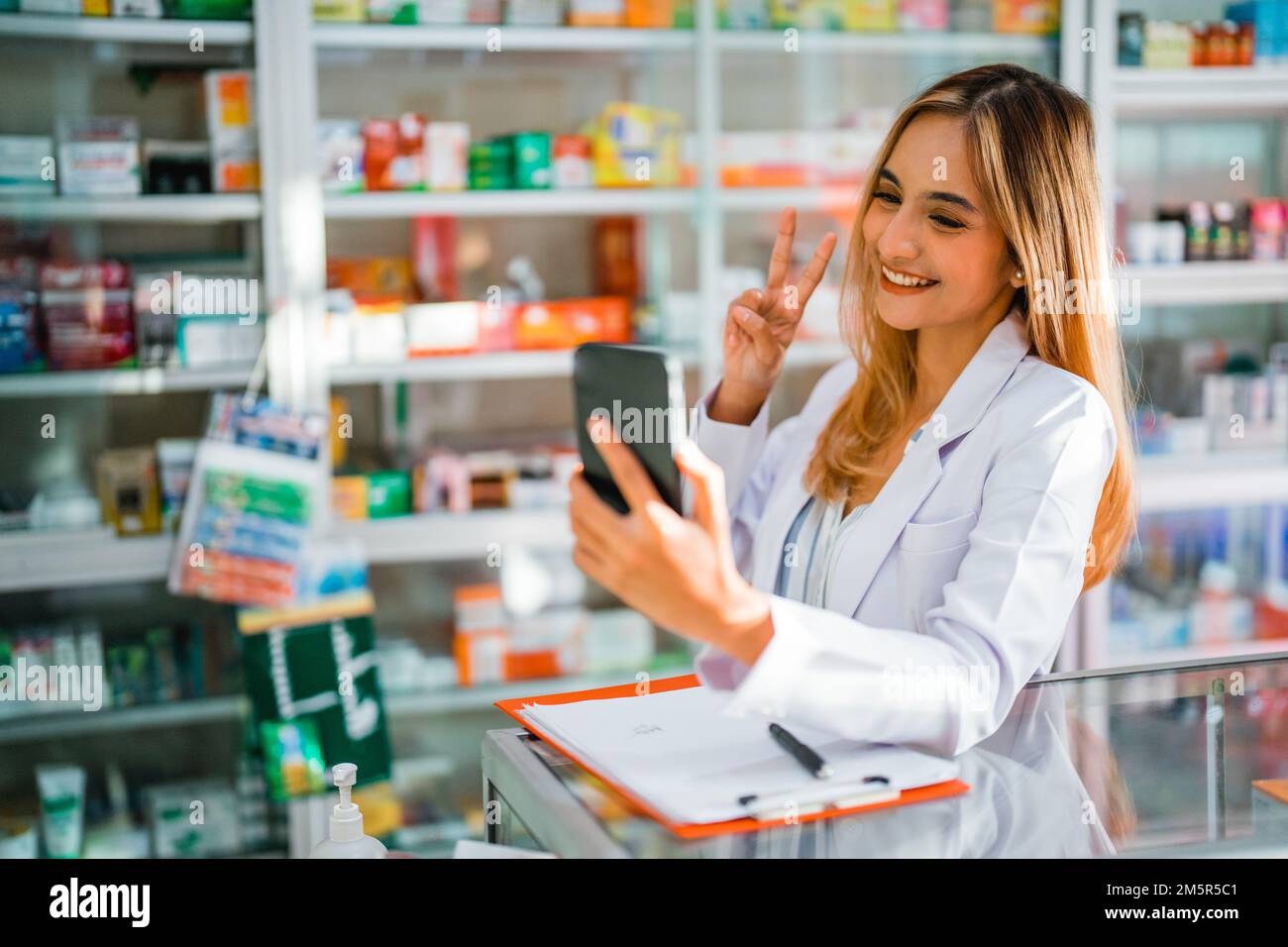 asian female pharmacist using mobile phone for selfie Stock Photo - Alamy
