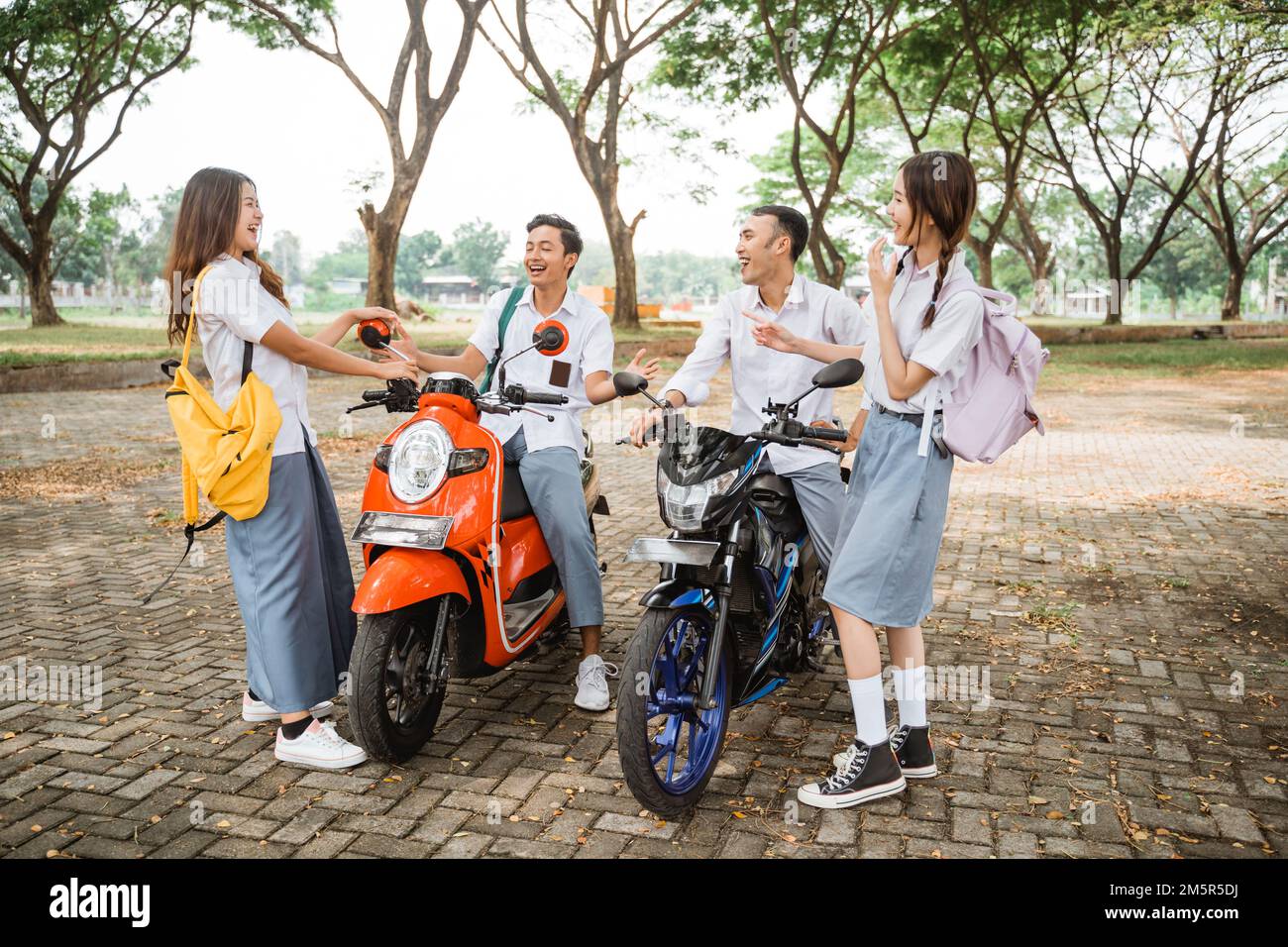 Four students in high school uniforms have fun riding motorbikes Stock ...