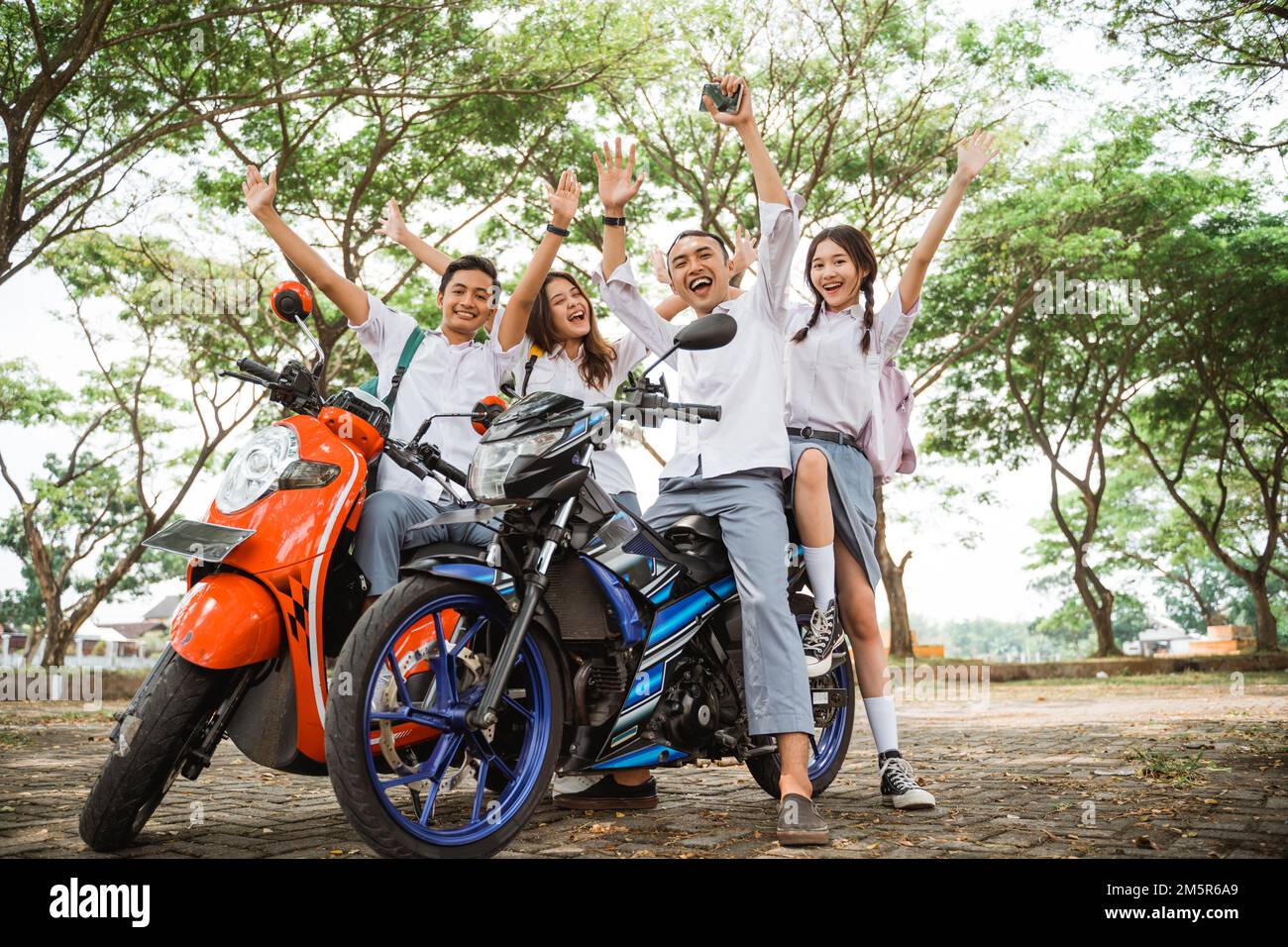 Four Asian high school students raise their hands celebrating ...