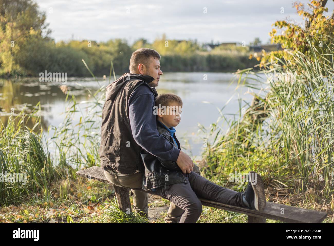 Father hugging his son outdoors on the bench. Precious moments between ...