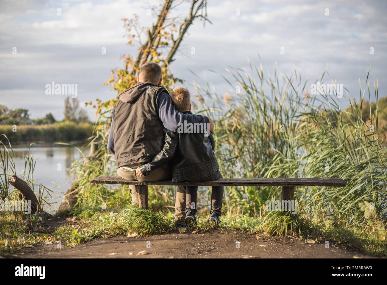 Father hugging his son outdoors on the bench. Precious moments between ...