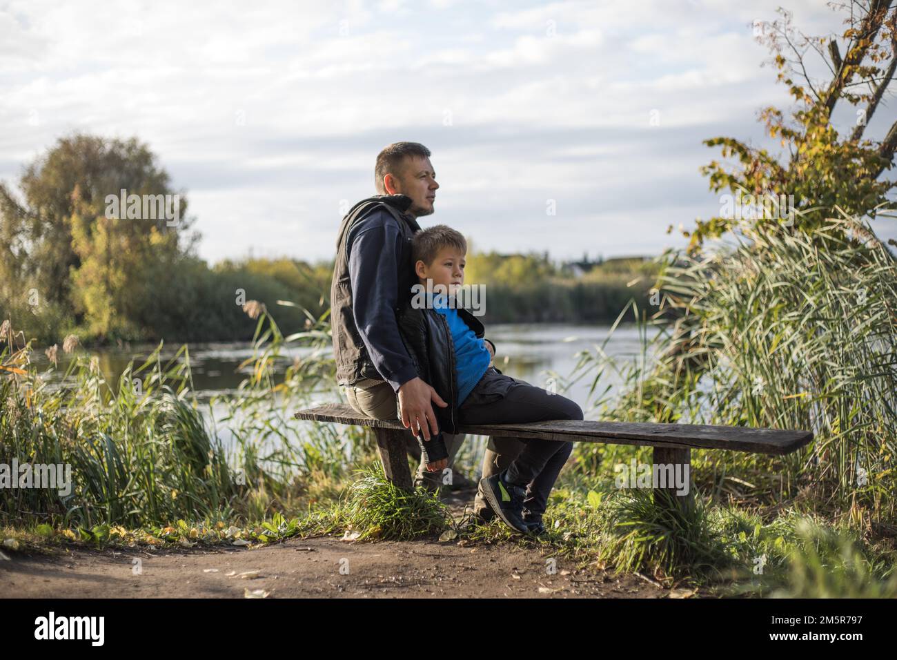Father hugging his son outdoors on the bench. Precious moments between ...