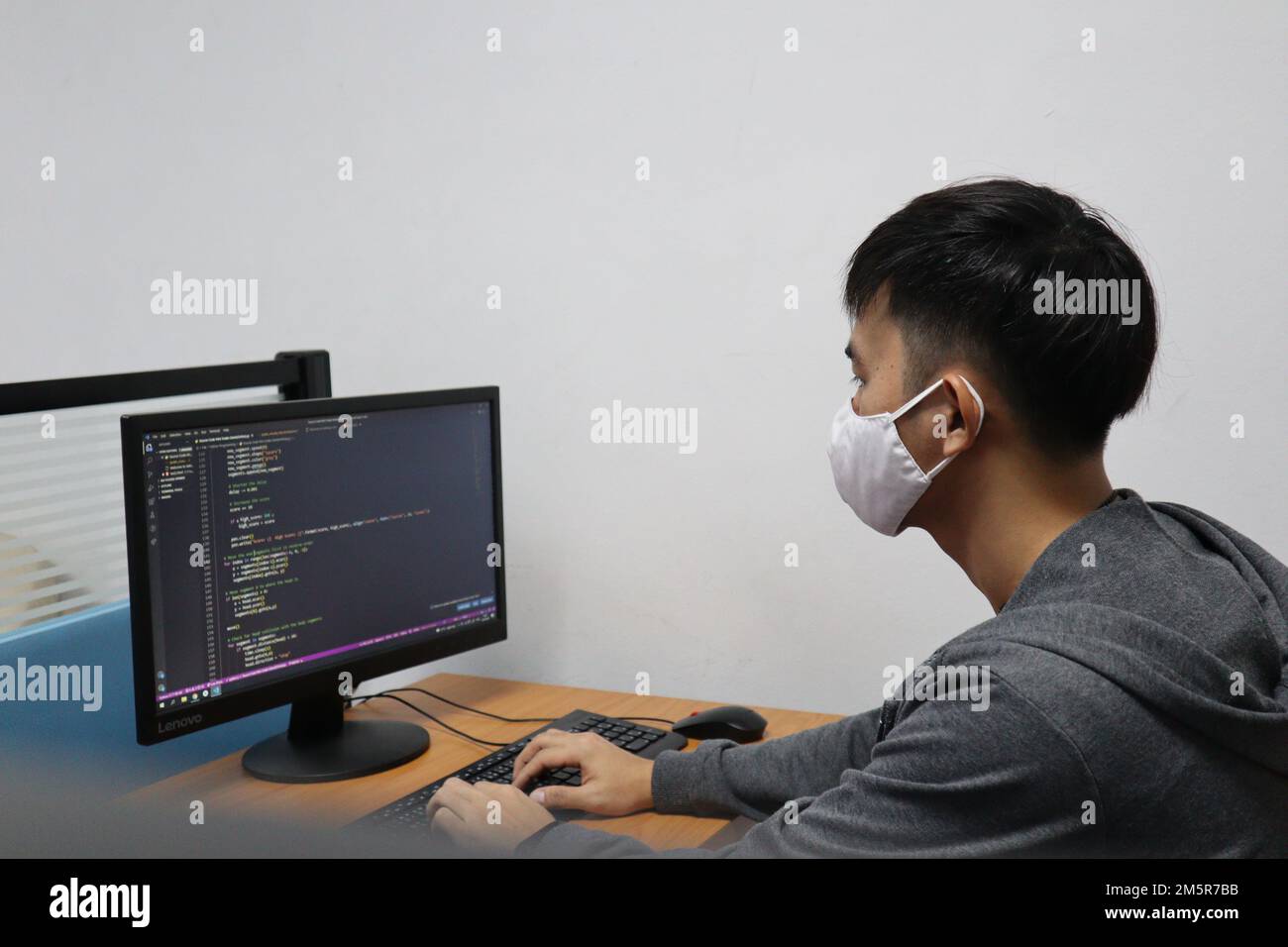 A young boy in a mask learning coding on his computer during the ...