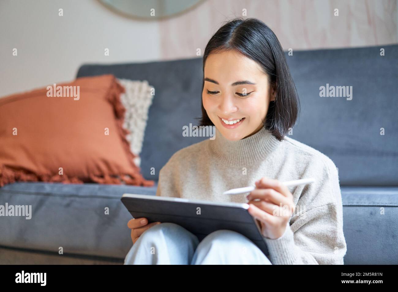 Creative young woman sitting with tablet and pen, drawing on digital ...
