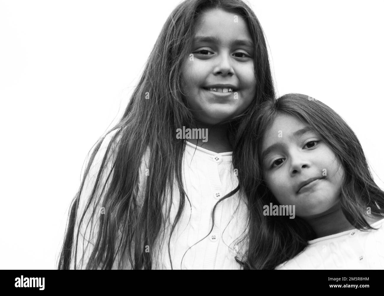 Portrait of smiling sisters against white background Stock Photo - Alamy