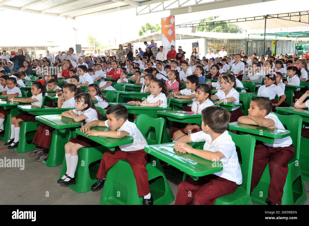 Elementary school children at their green colored tables and benches ...