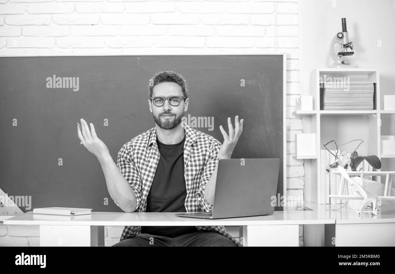smiling adult man tutor sitting in classroom at blackboard, education ...