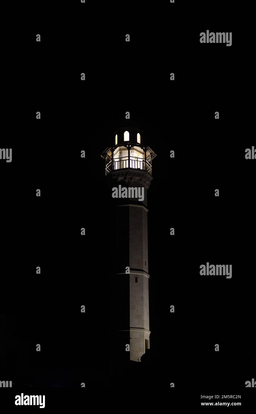 A tall illuminated lighthouse against a dark night sky Stock Photo - Alamy