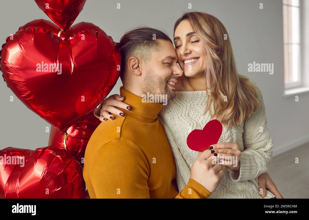 Young couple in love in romantic atmosphere is sitting among heart ...