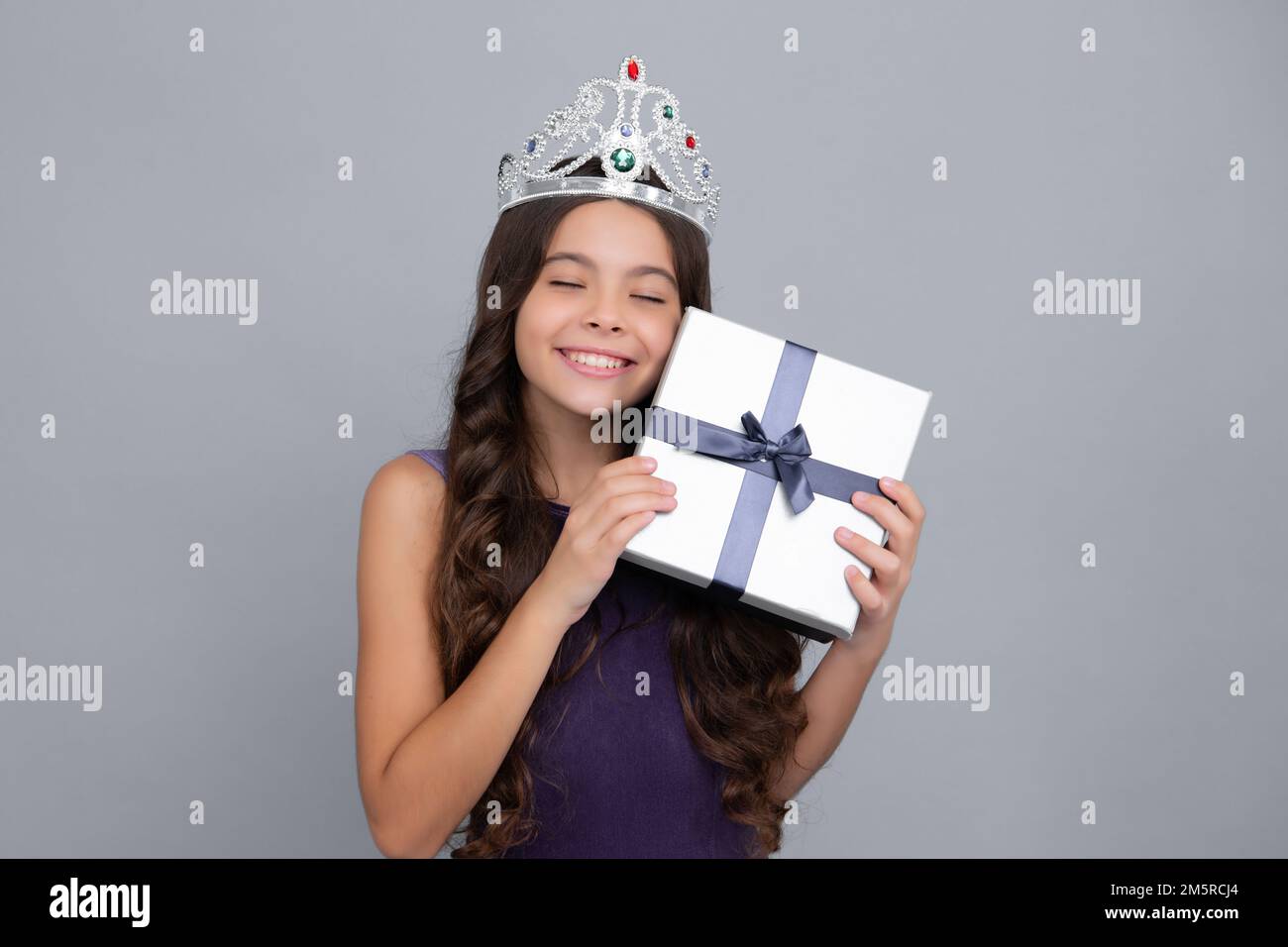 Child princess in crown dreaming. Teenager child with gift box, studio ...