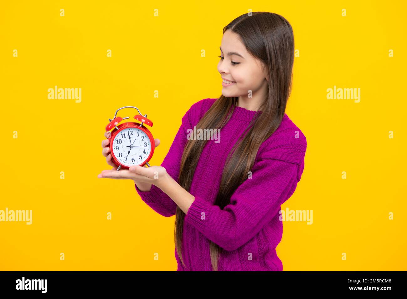 Punctual teen girl checking time. Child with alarm clock showing time ...