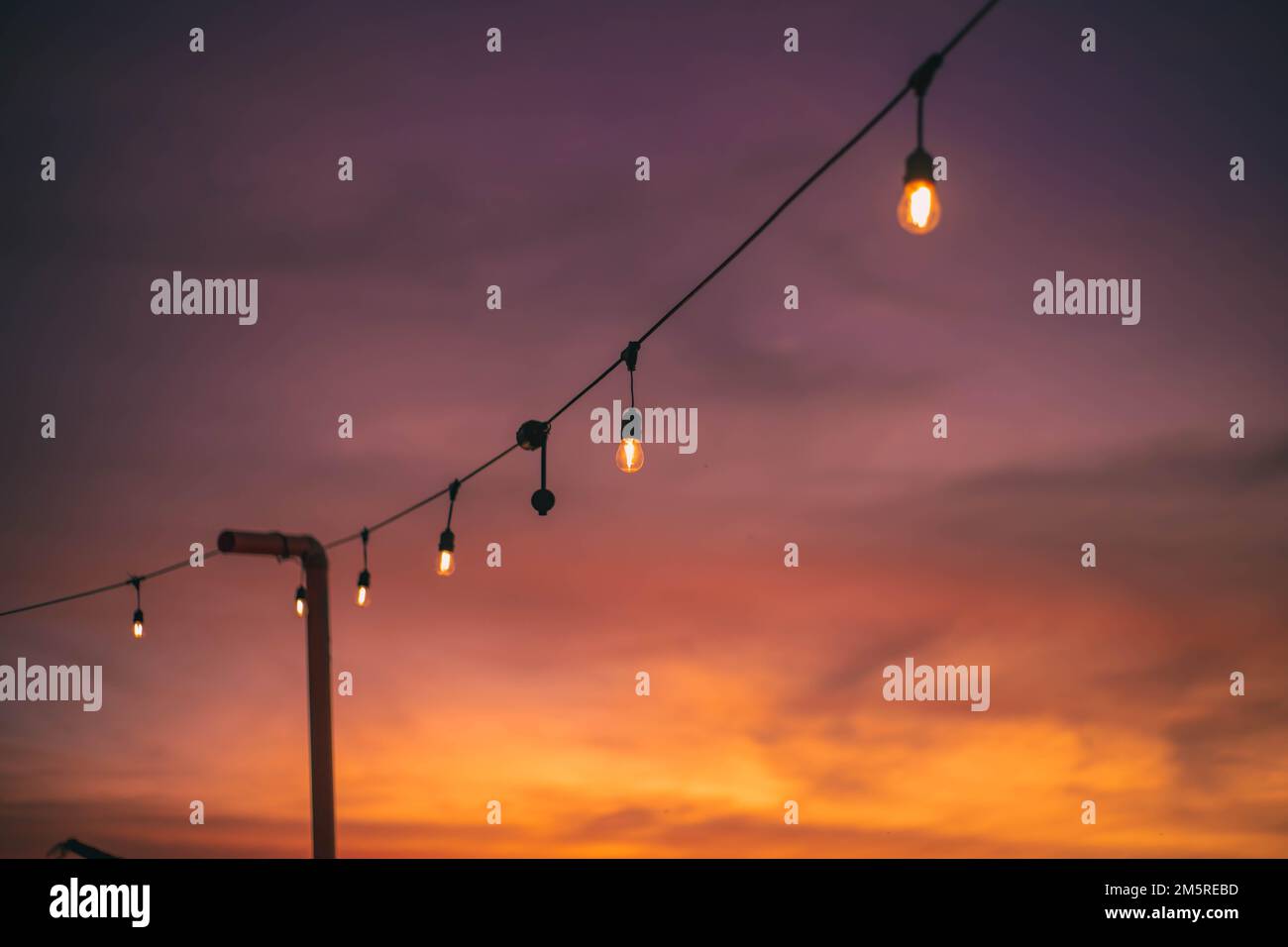 An image of a wire with light bulbs during a beautiful sunset Stock ...