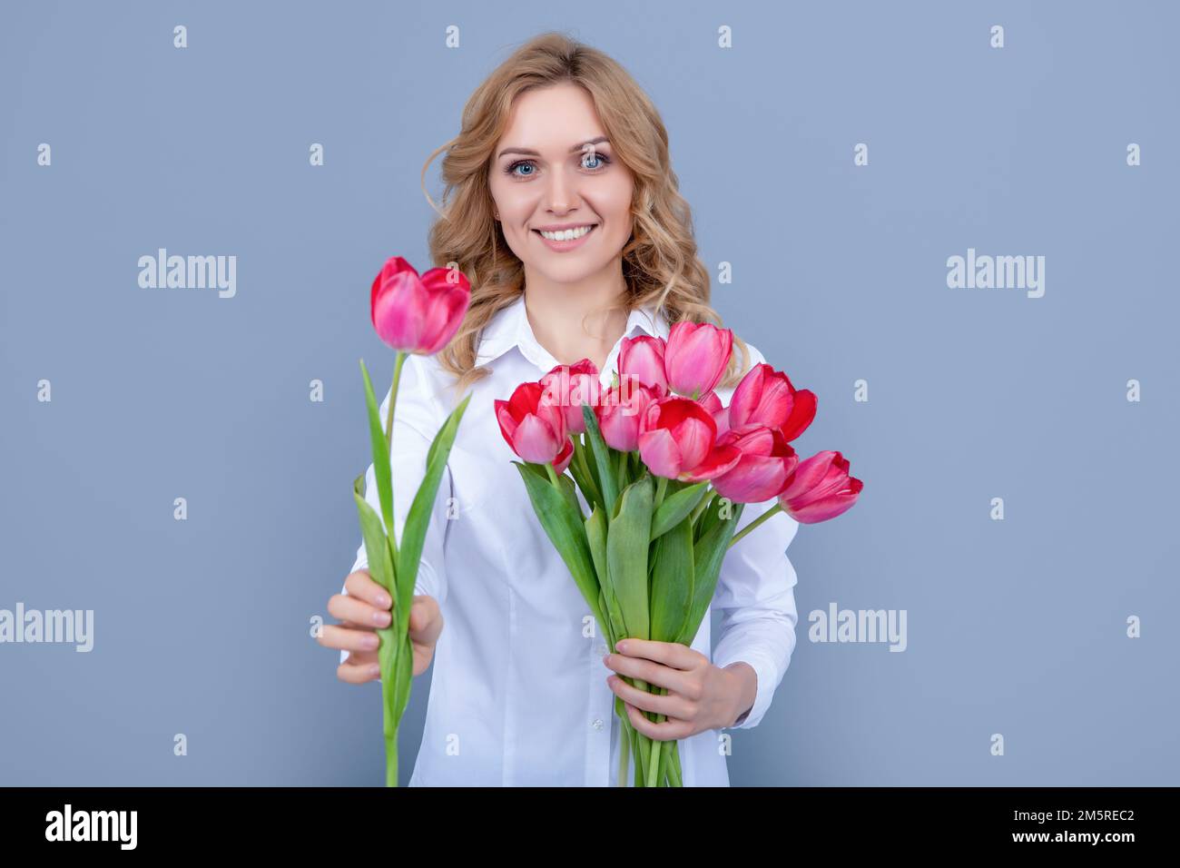 young woman smile give spring tulip flowers on grey background Stock ...