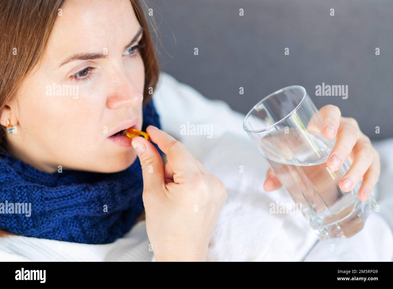 Influenza treatment. Flu-sick woman, wrapped in warm scarf and blanket ...