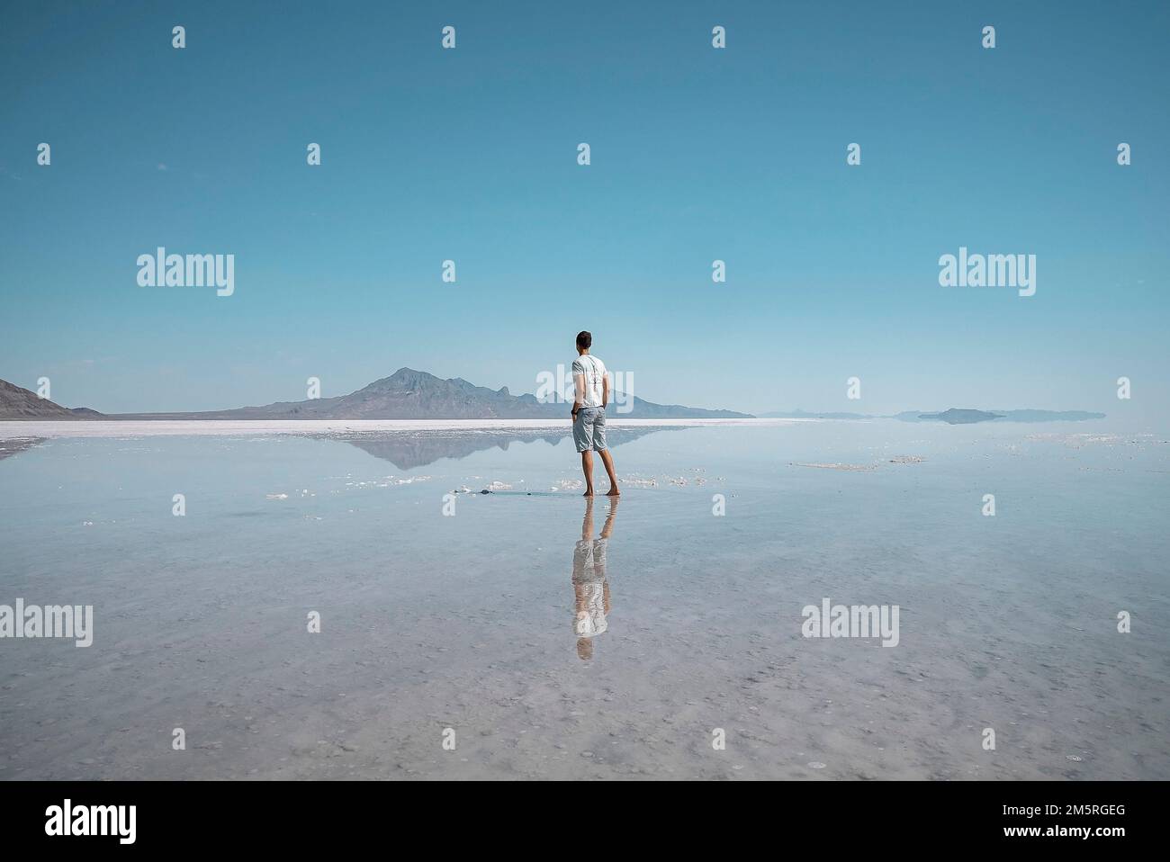 Man sightseeing Bonneville salt flat and mountains during summer ...
