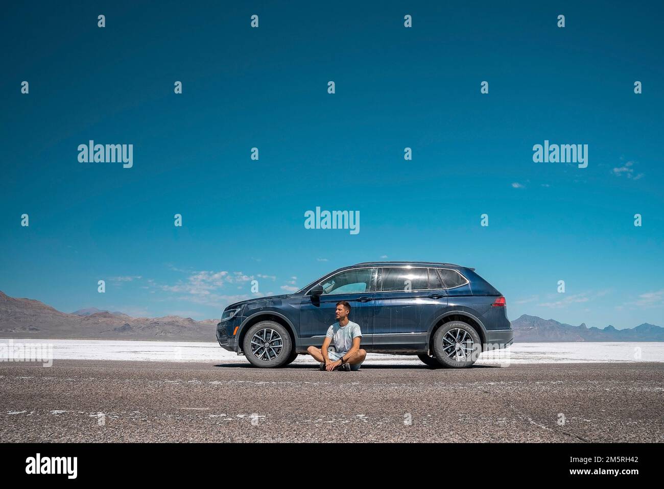 Tourist relaxing by car at Bonneville salt flat with sky in background ...