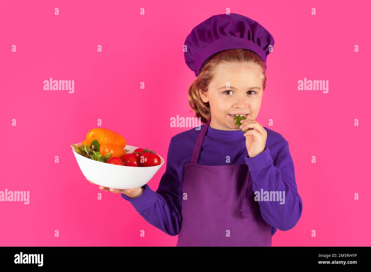 Child cook hold plate with vegetable. Kid chef cook, studio portrait ...
