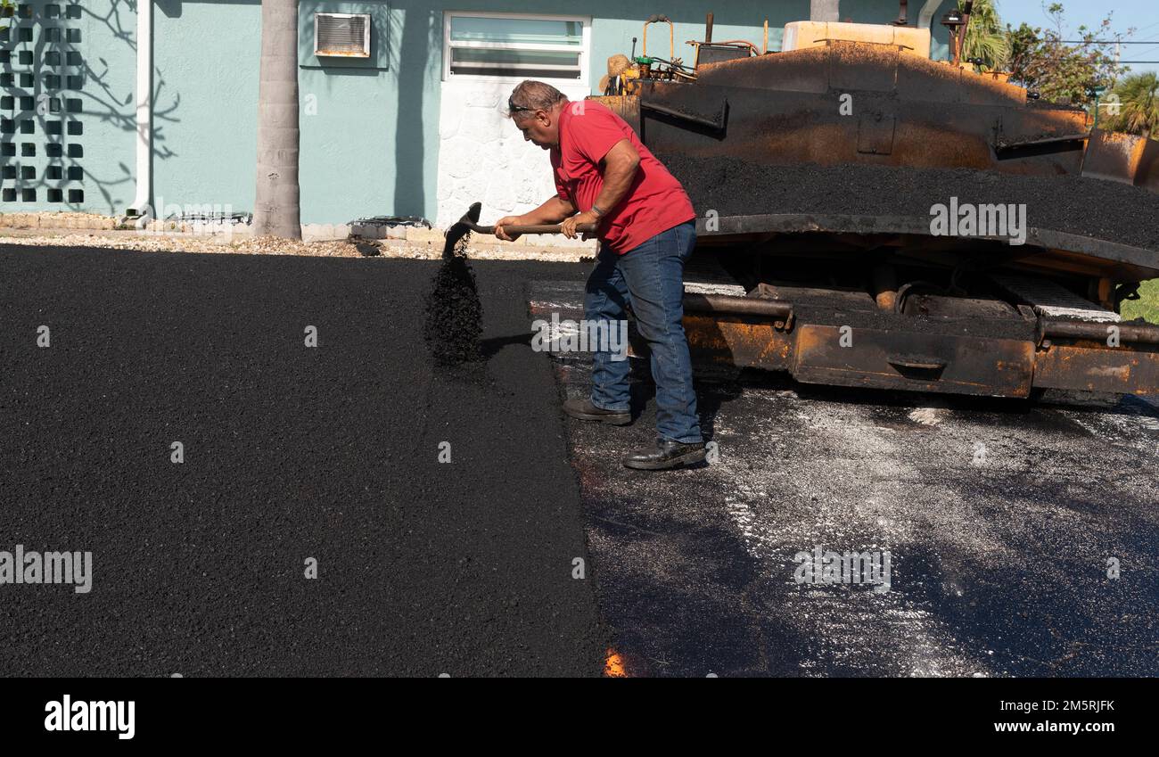 Cocoa Beach, Florida, USA, 2022. Asphalting worker using a shovel to ...