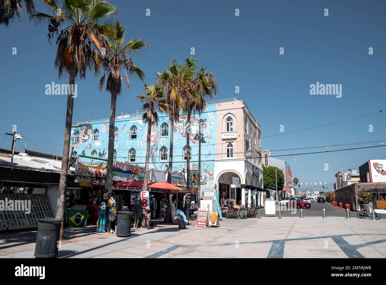 View of shops and palm trees on boardwalk at Venice beach during sunny ...