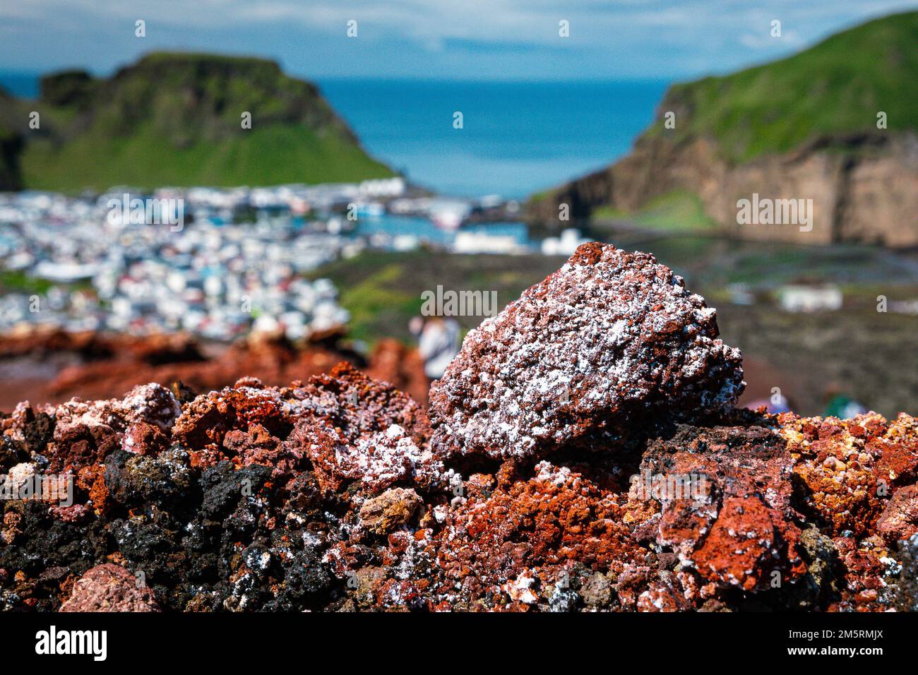 A closeup shot of the red minerals in Iceland with green islands in the ...