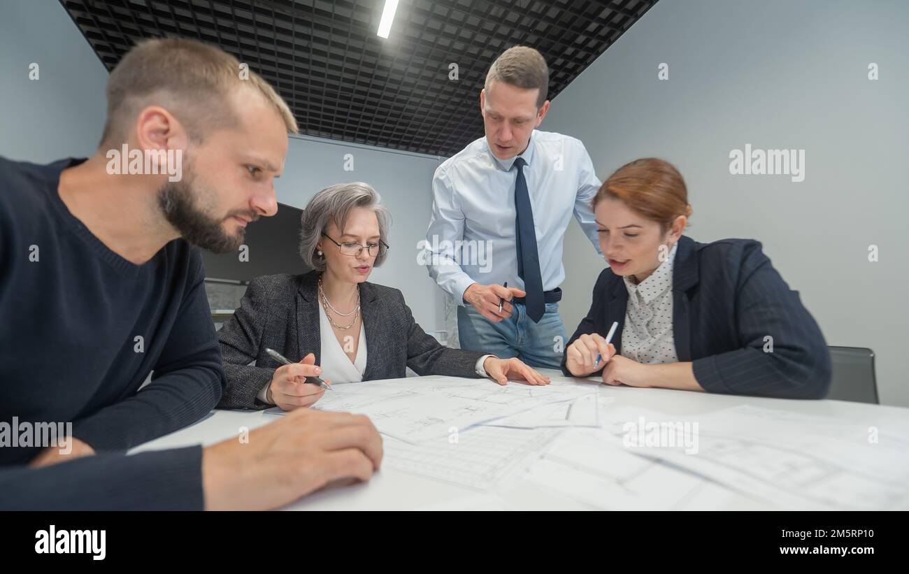 The boss gives instructions to three employees in the office conference ...