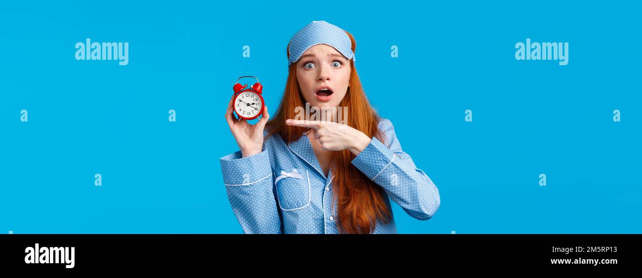 Shocked and concerned, worried cute redhead girl pointing at alarm ...