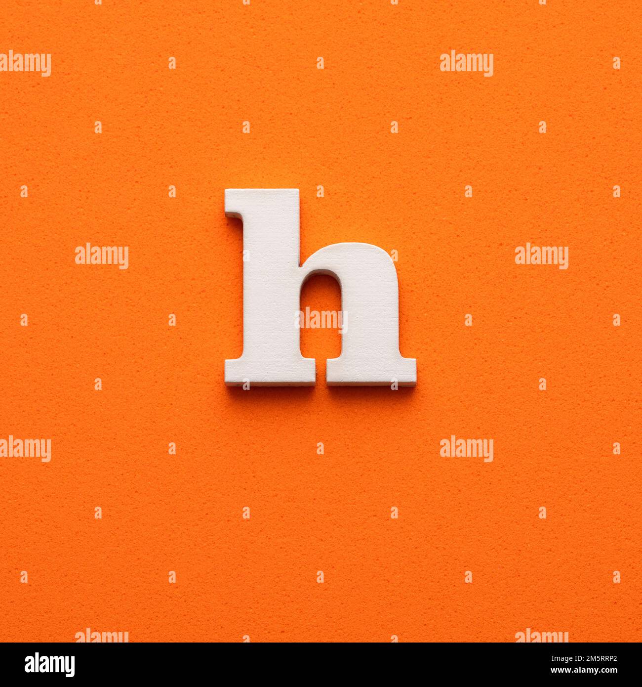 h white lowercase letter - Background in orange foamy Stock Photo - Alamy