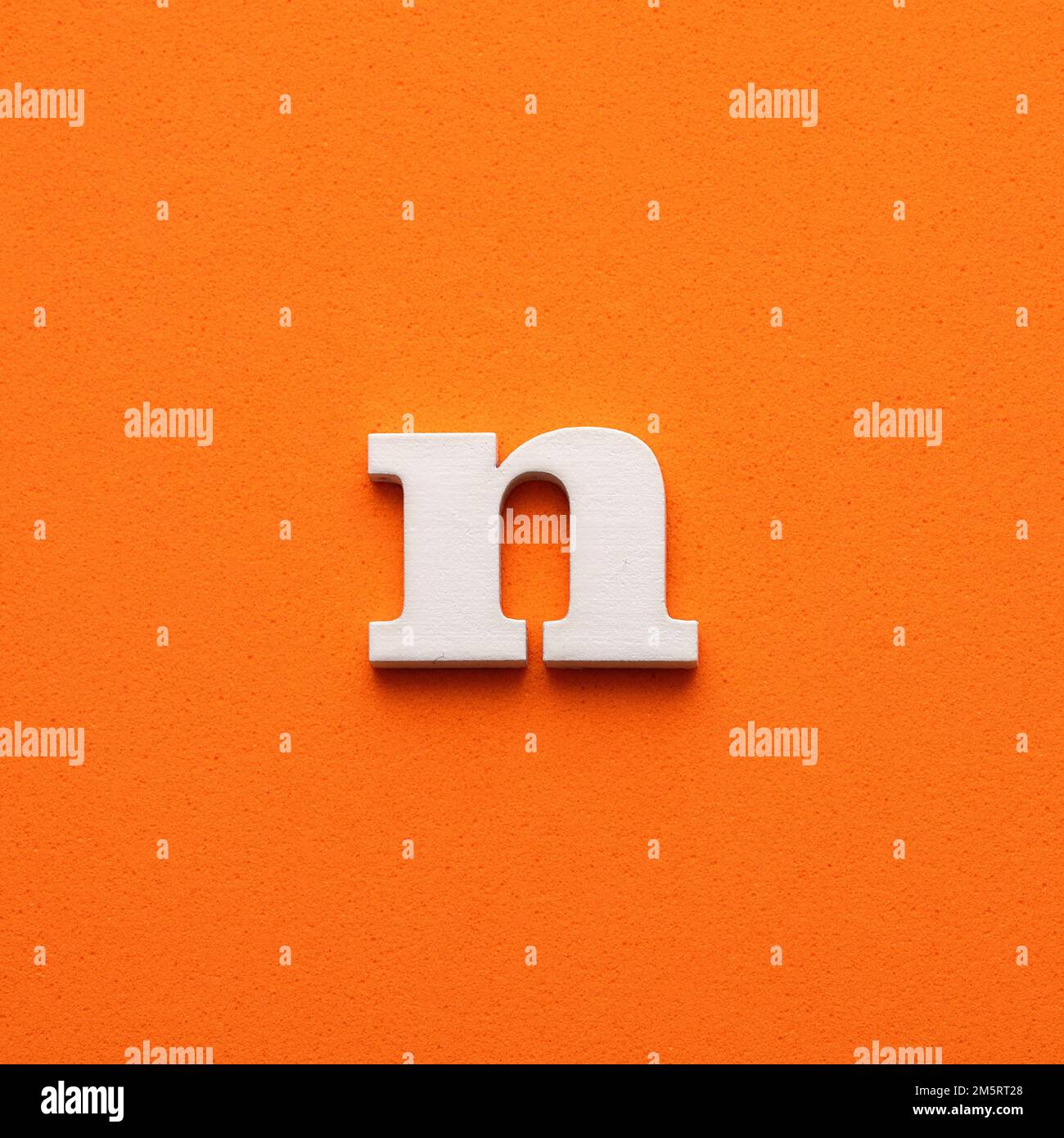 n white lowercase letter - Background in orange foamy Stock Photo - Alamy