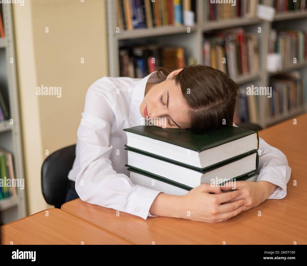 Young woman sleeping on textbooks in a public library Stock Photo - Alamy