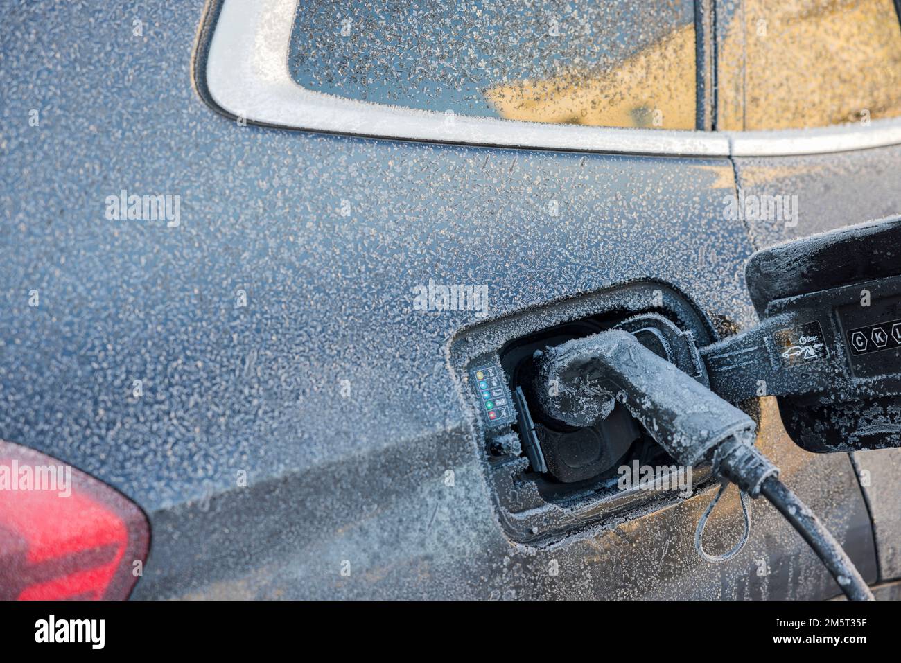 View of charging an electric car on frosty winter day in parking of ...