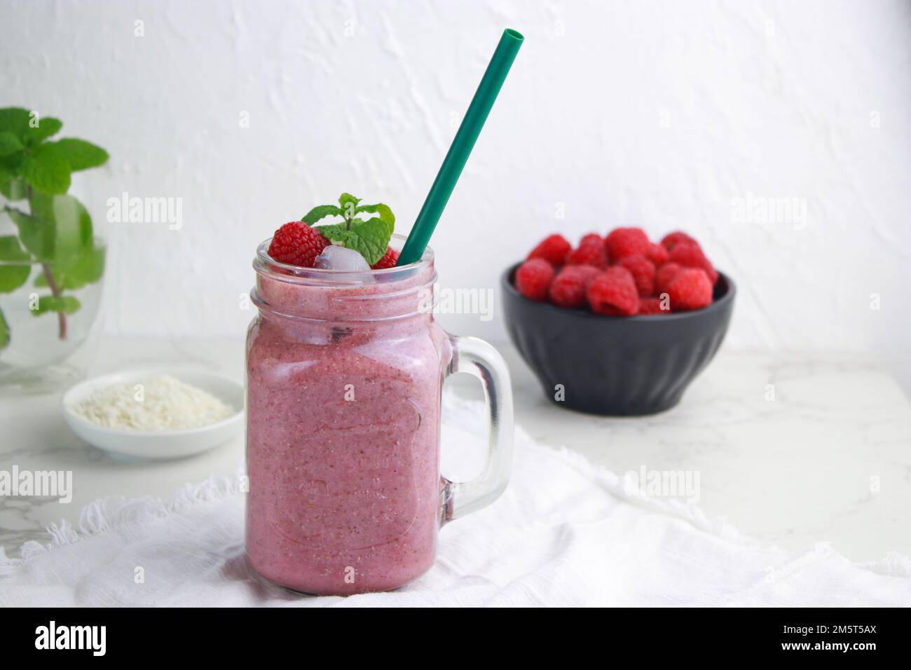 raspberry coconut smoothie with ice in a jar with straw, white ...