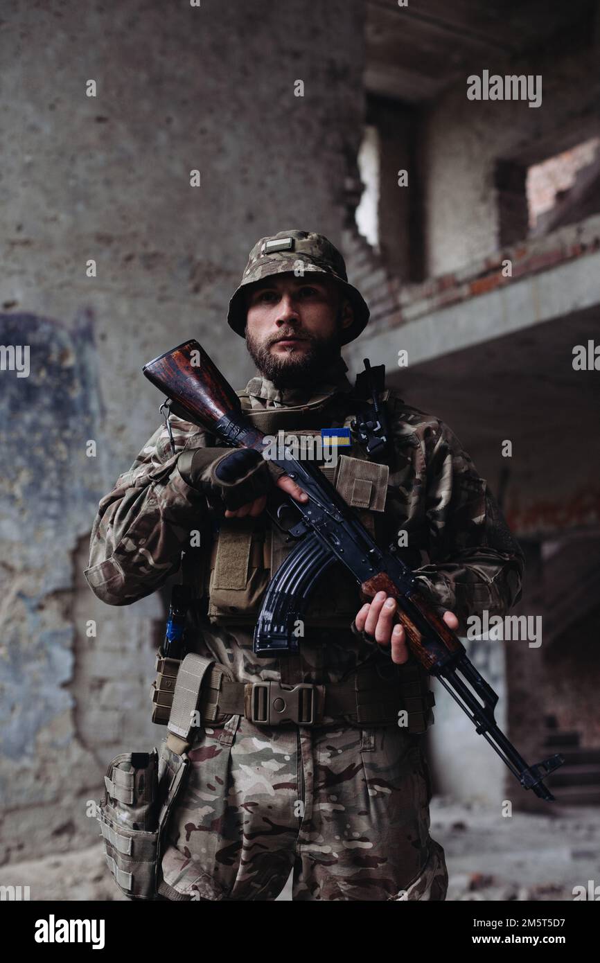 A Ukrainian military man poses against the background of destroyed ...