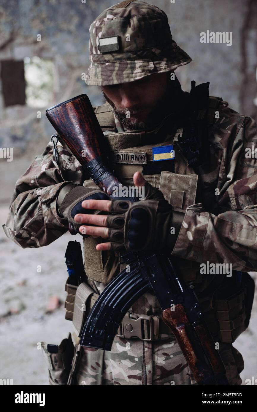 A Ukrainian military man poses against the background of destroyed ...
