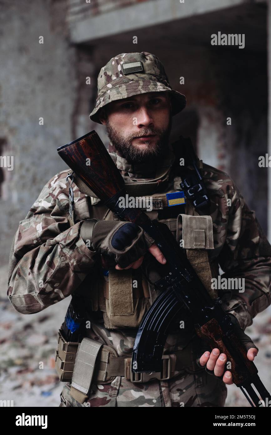 A Ukrainian military man poses against the background of destroyed ...