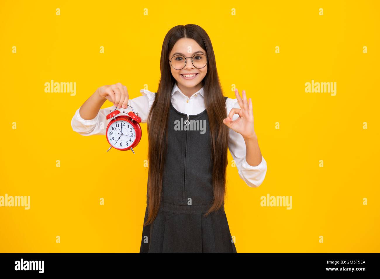 Teen student girl hold clock isolated on yellow background. Time to ...
