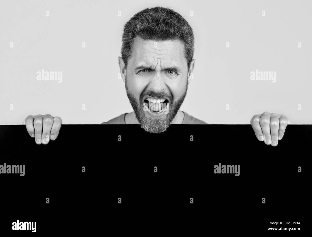 shouting bearded man behind blank black paper banner with copy space ...