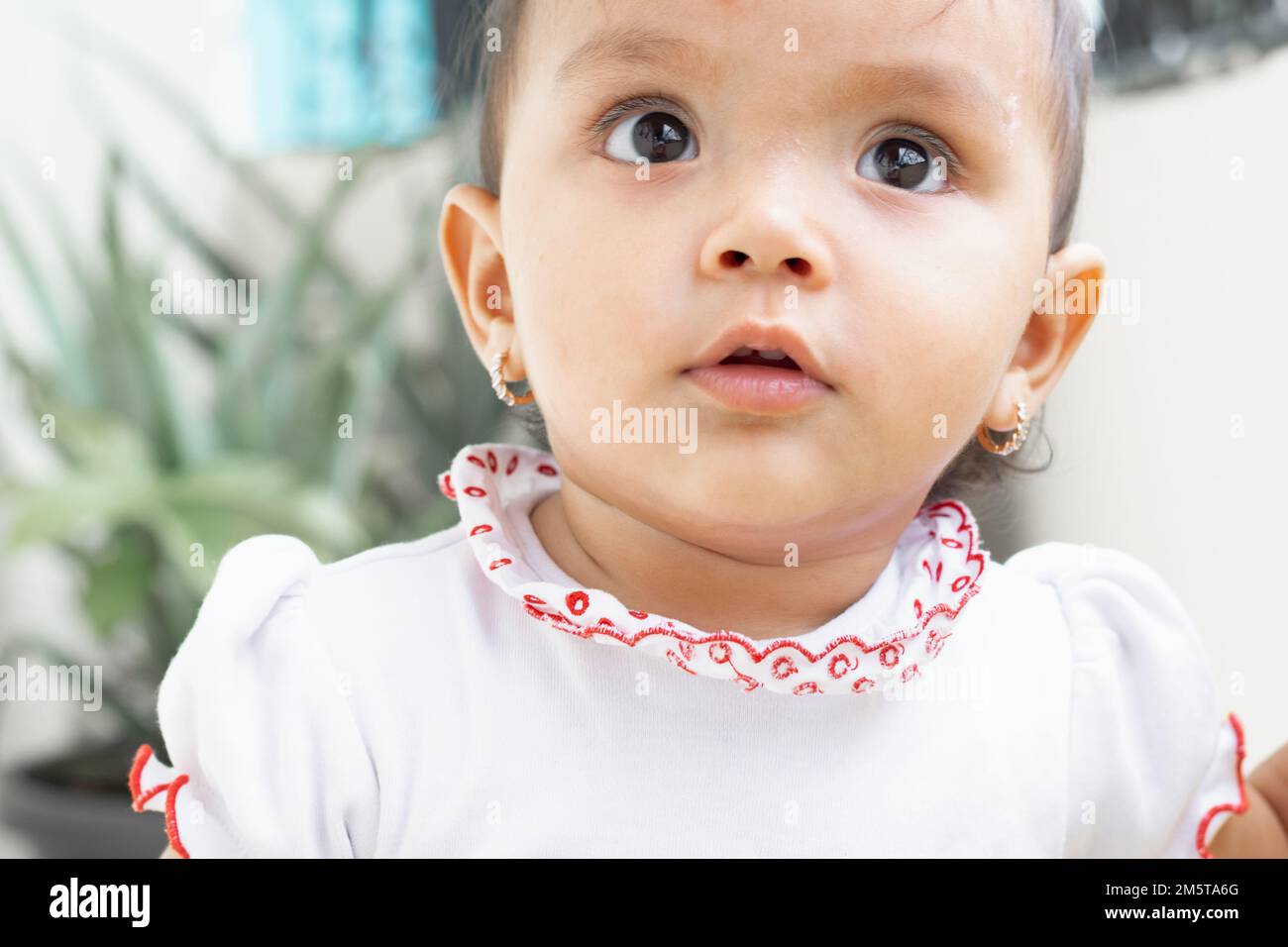 close-up of beautiful brunette baby girl, with a frightened expression ...