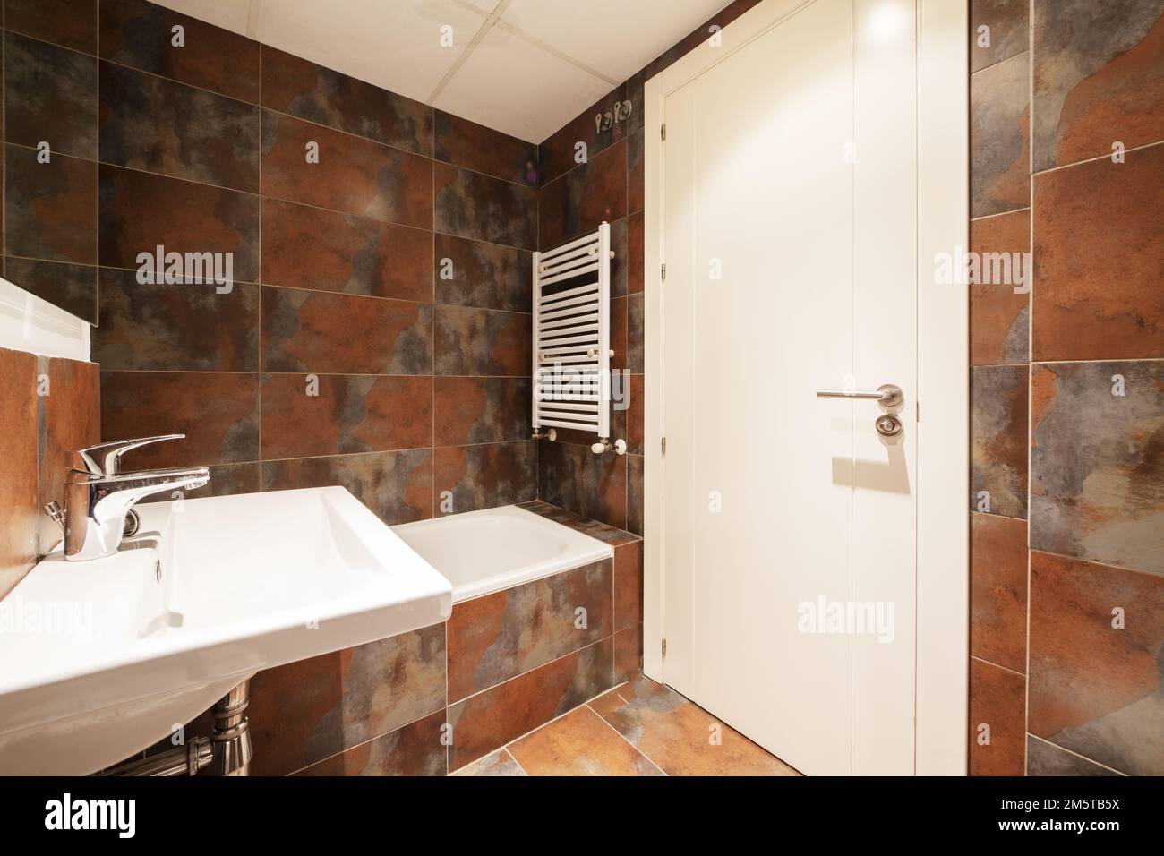 Bathroom with hanging porcelain sink, matching bathtub, heated towel ...