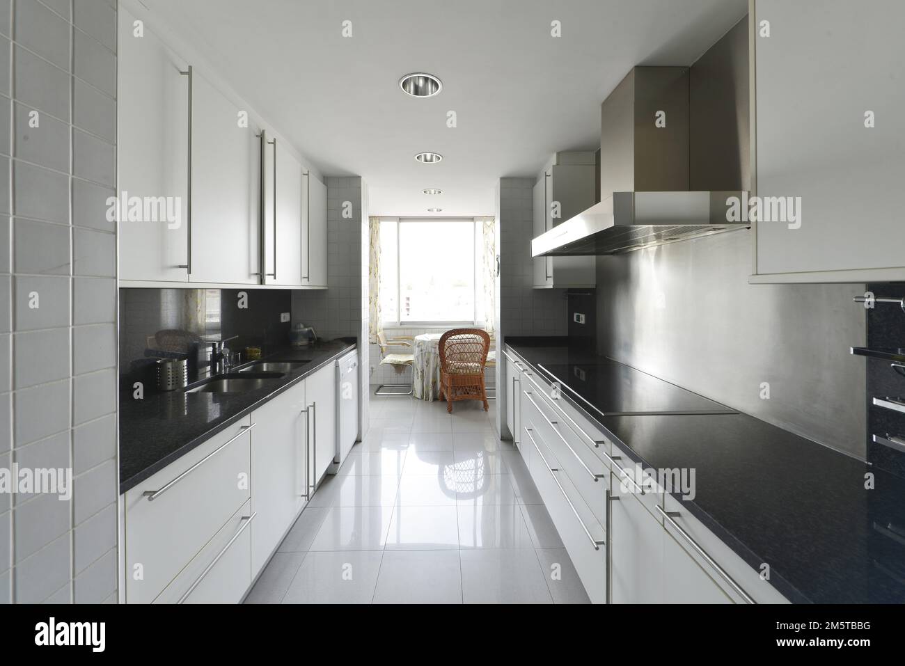 elongated kitchen with black marble countertop on white furniture with ...