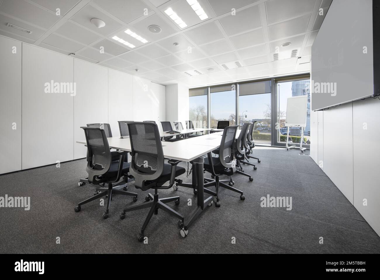 long white boardroom table with black swivel chairs on gray carpet ...