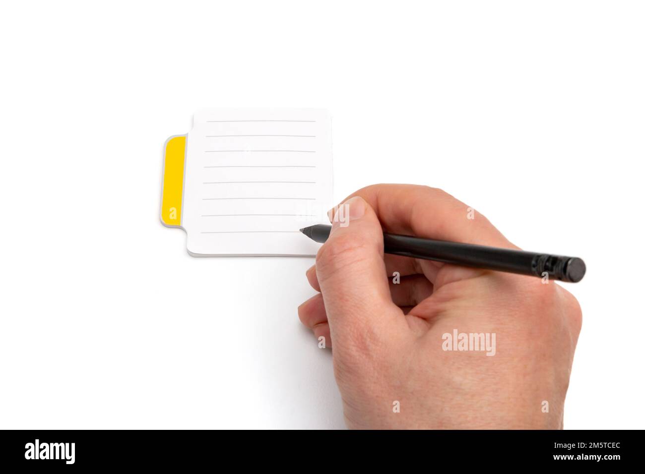 Hand with pencil writing on blank small lined sticky notes with yellow ...