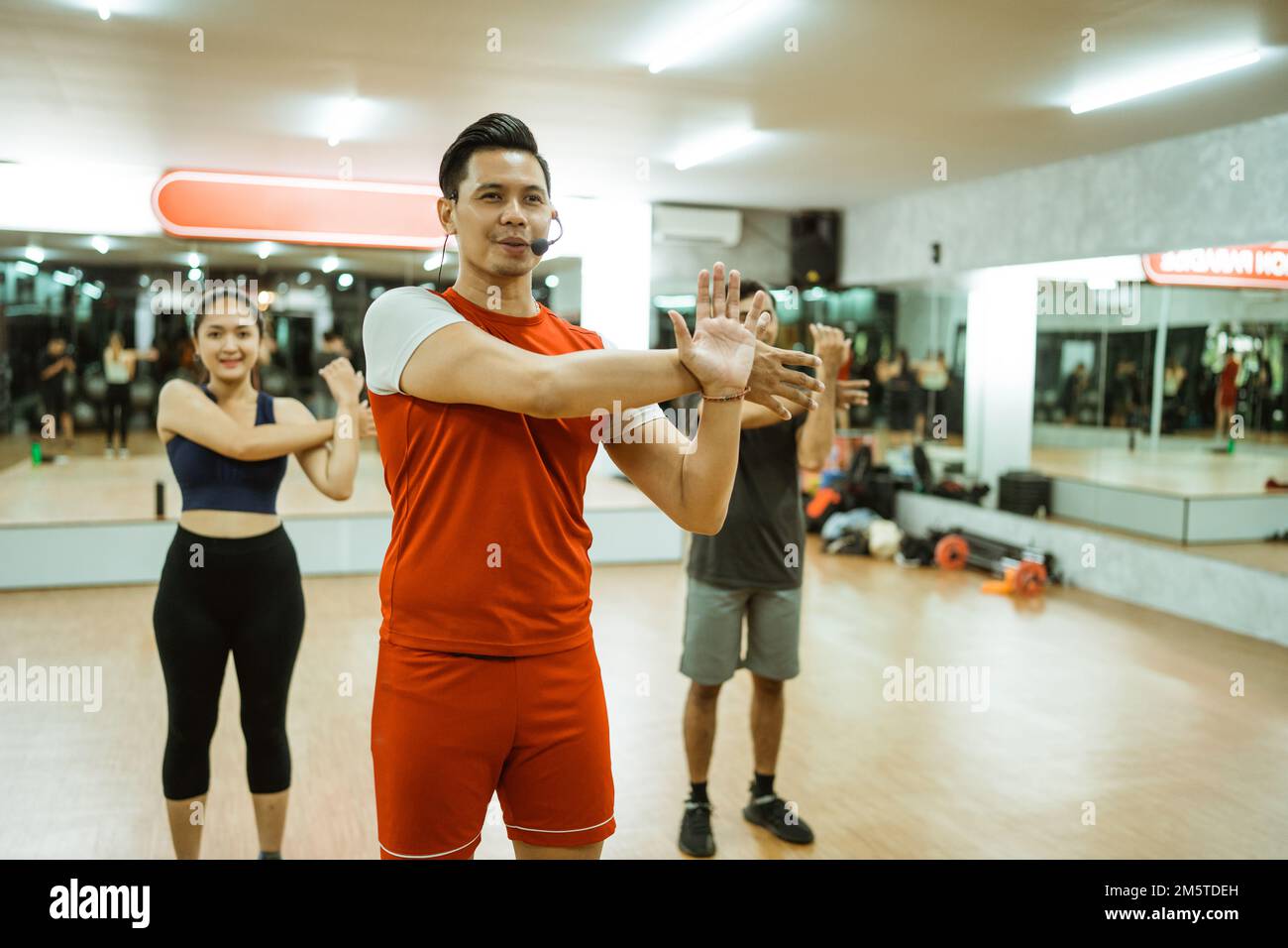 male instructor leading exercise with arm muscle stretching movements ...