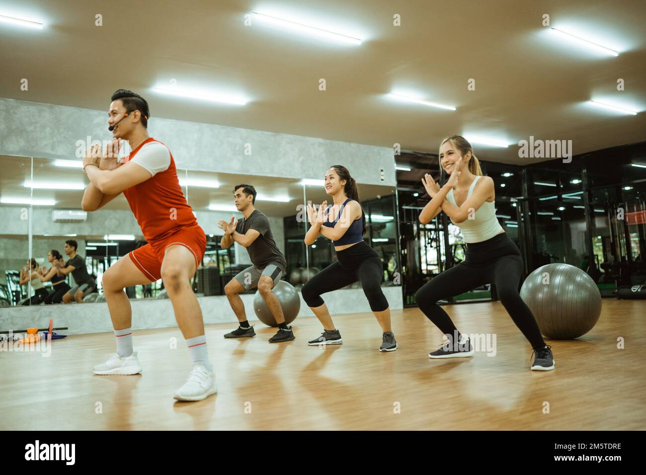 male instructor doing squats together with body combat participants ...