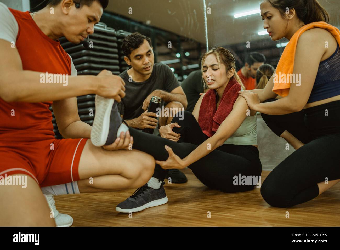 Asian woman with leg cramps is helped by her friends Stock Photo - Alamy