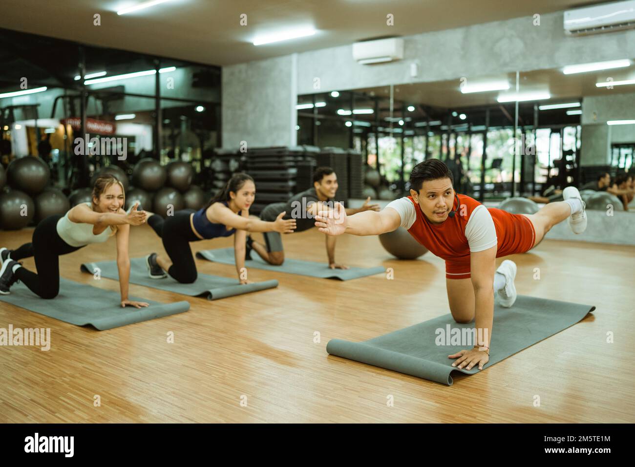 Male instructor doing balancing moves with group of sporty people Stock ...