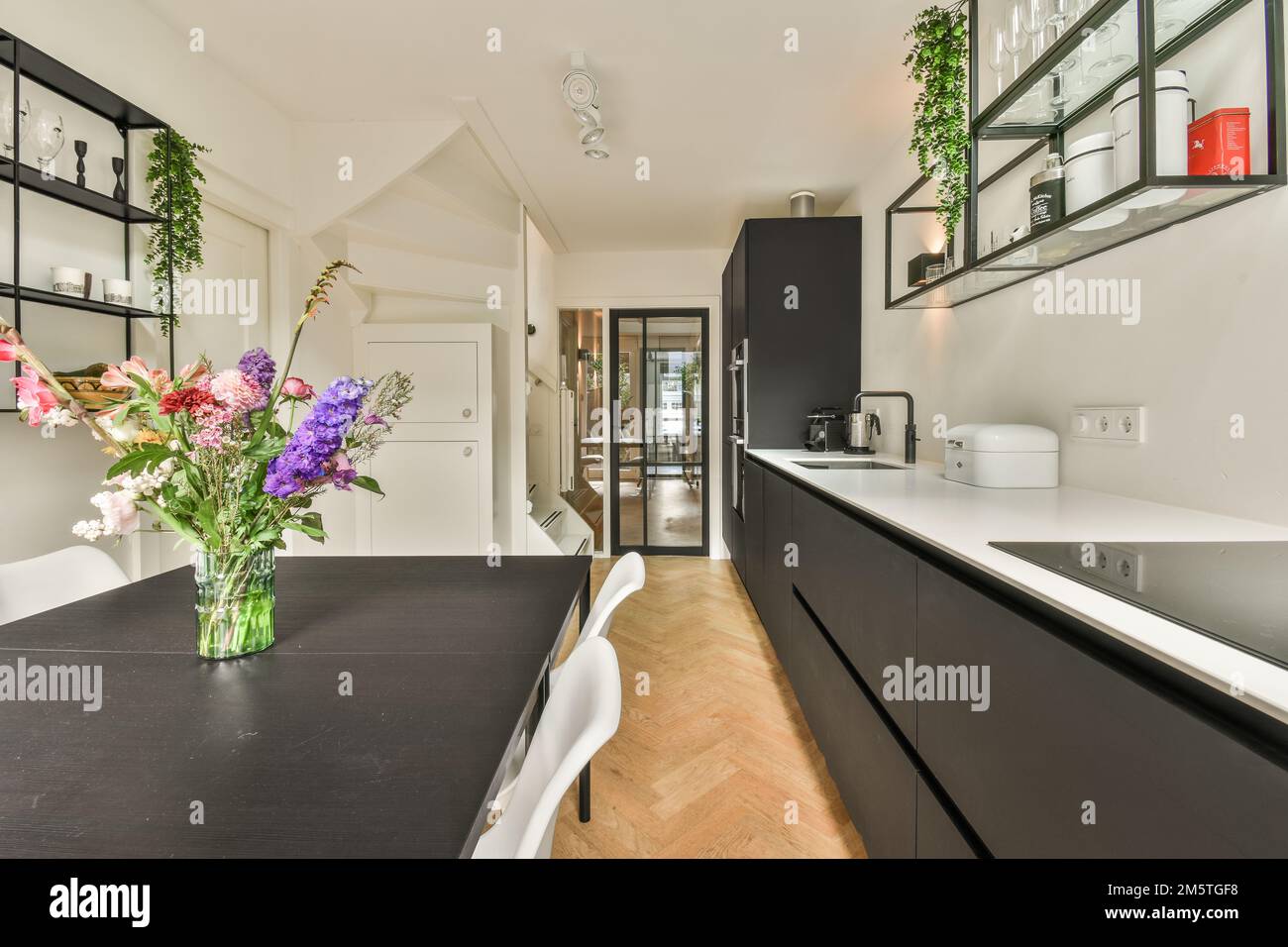 a kitchen with flowers in a vase on the counter top and black cabinet ...