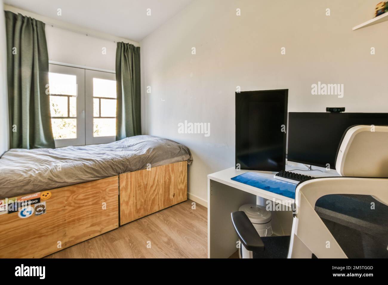 a bedroom with a bed, desk and computer on the wall next to it is a ...