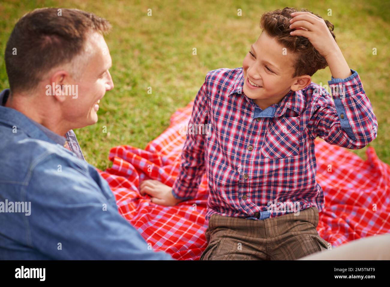 Chilling with dad. a father and son talking together while lying in a ...