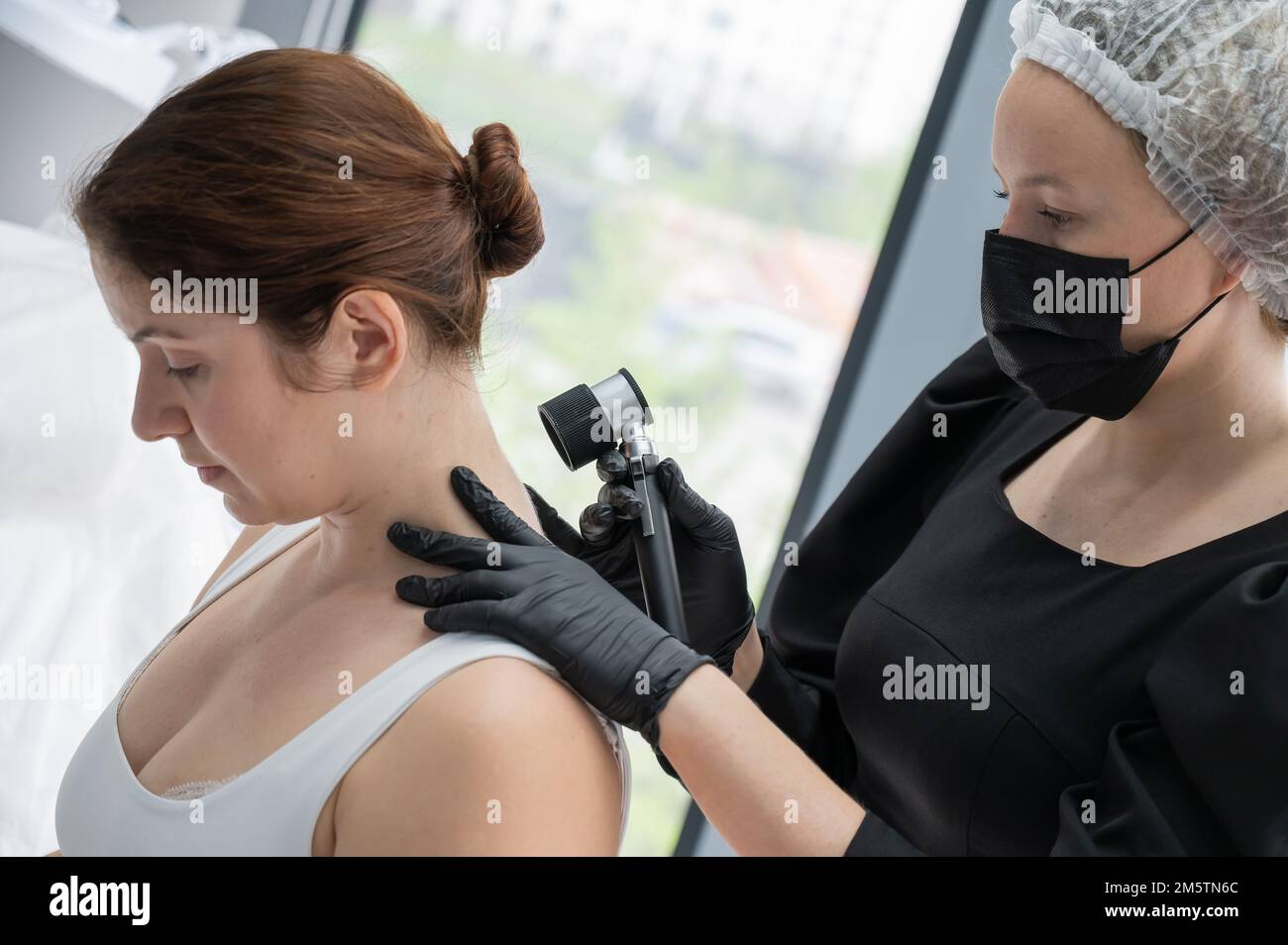A dermatologist examines a patient's mole through a dermatoscope Stock ...