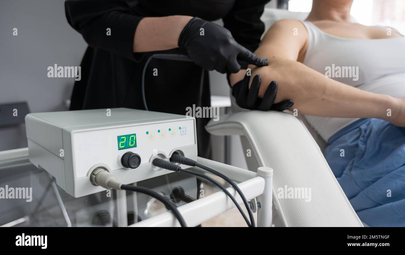 Dermatologist removes a mole on a patient's arm using an ...